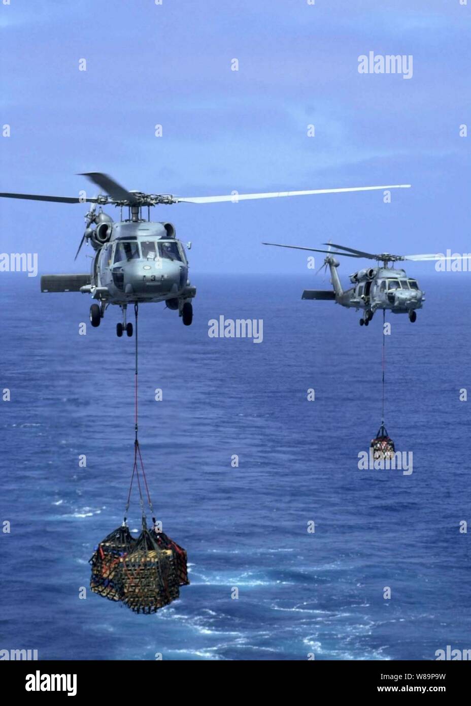 Two U.S. Navy Seahawk helicopters transfer supplies from the USS Camden ...