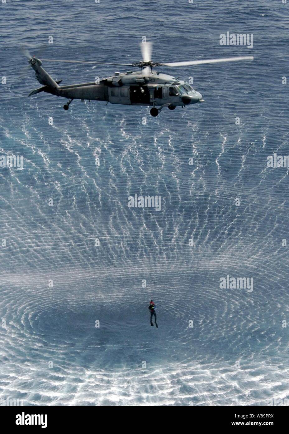 The rotor wash from a U.S. Navy MH-60S Knight Hawk helicopter makes a ...