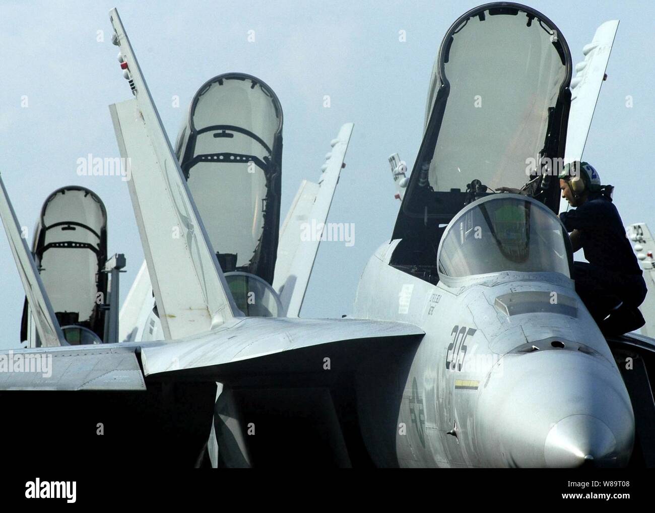 U.S. Navy Airman Jason Rickards adjusts some equipment in the cockpit ...