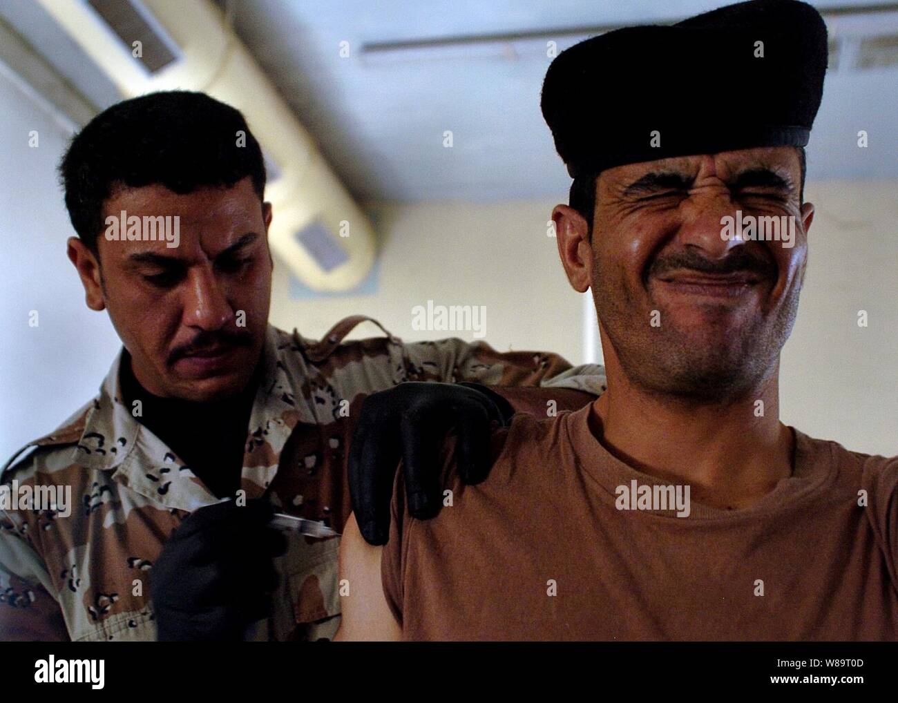 An Iraqi army soldier winces as an Iraqi army medic vaccinates him ...