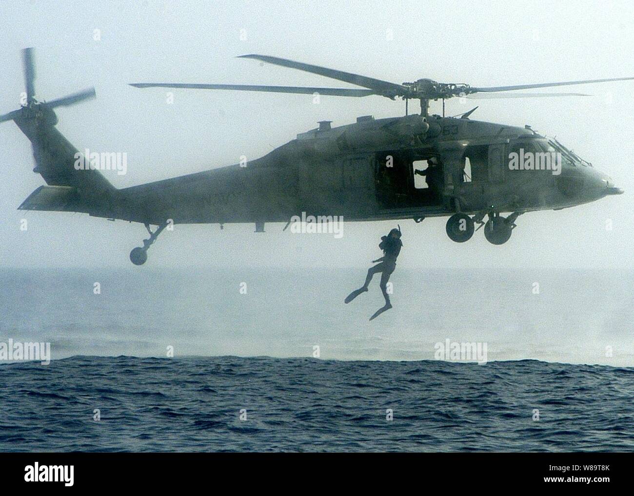 A Navy search and rescue swimmer jumps out of an MH-60S Seahawk ...