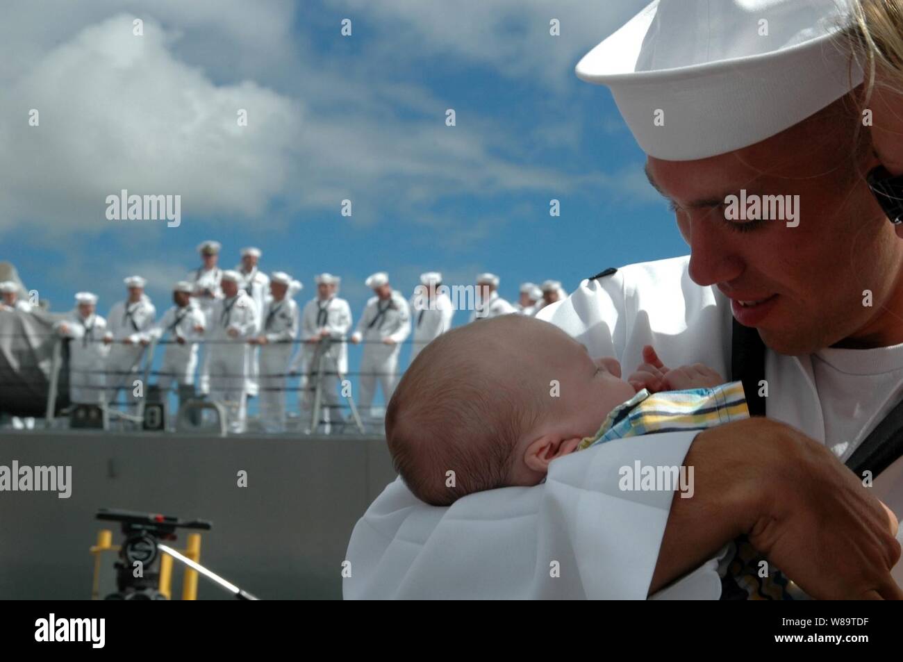 A U.S. Navy sailor holds his child for the first time after returning ...