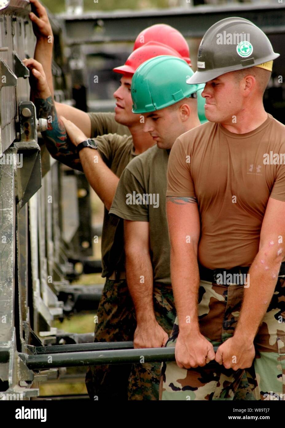 U.S. Navy Seabee Petty Officer 3rd Class Mark Crubaugh (right) works ...