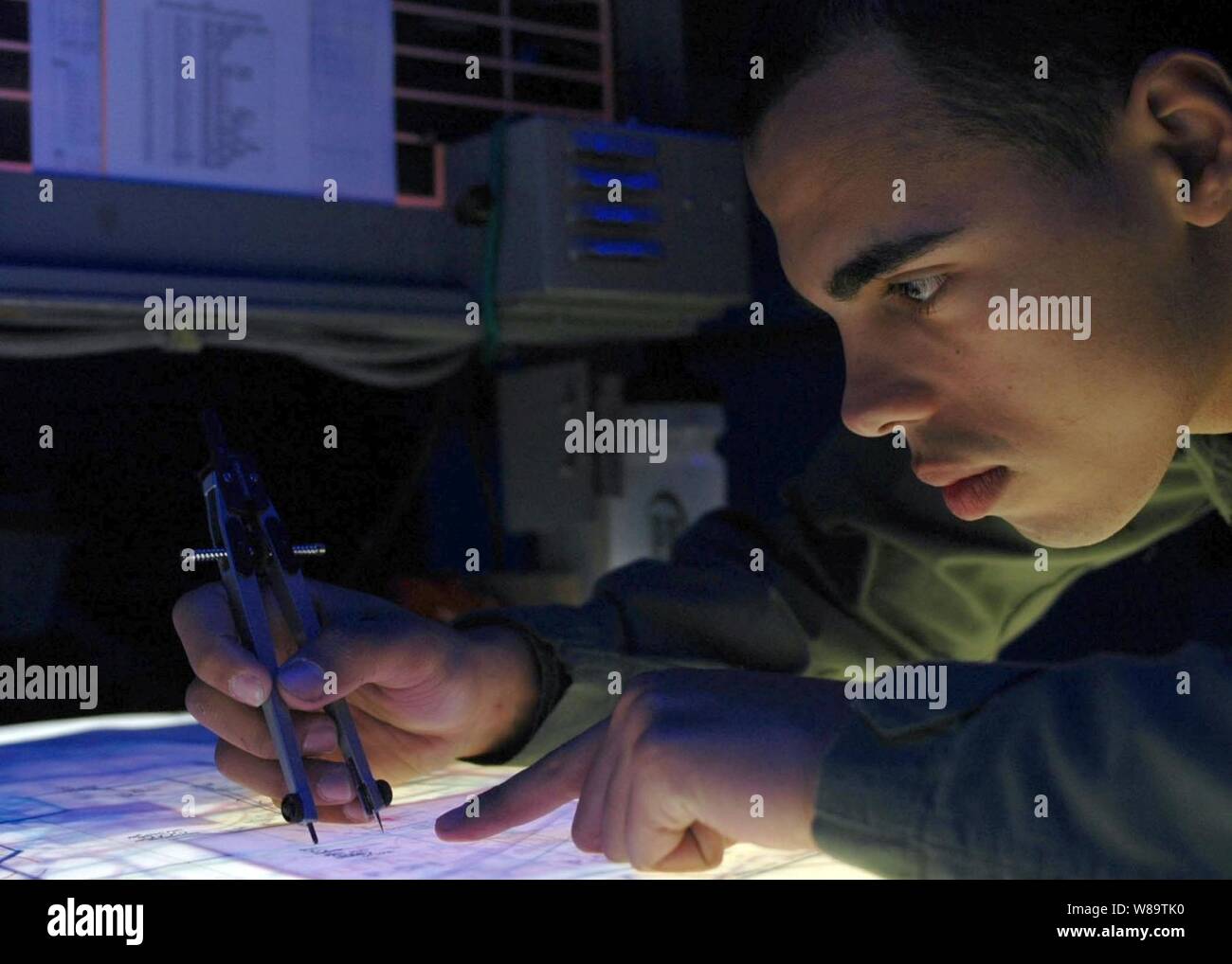 Navy Petty Officer 3rd Class Lawrence Rosado performs tactical plotting ...