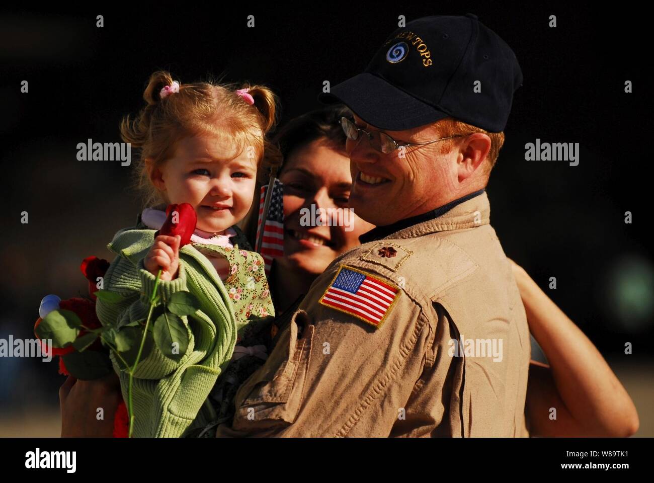 U.S. Navy Lt. Cmdr. Kevin Downey holds his daughter as his wife looks ...