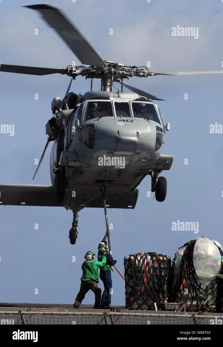 U.S. Navy sailors from the USNS Bridge (T-AOE 10) hook up cargo to an MH-60S Knight hawk ...