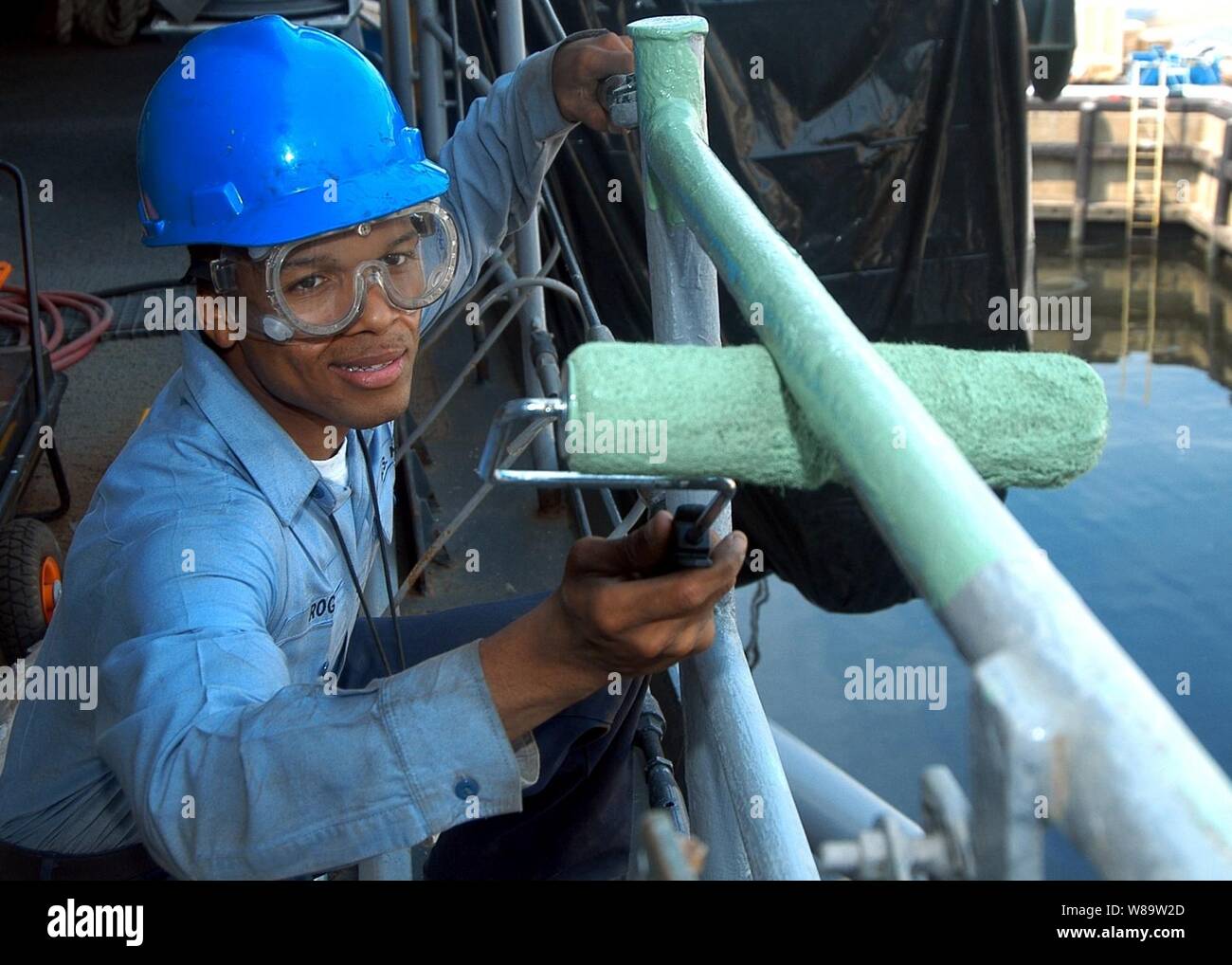 Navy Seaman Michael Rogers applies primer to a railing in preparation ...