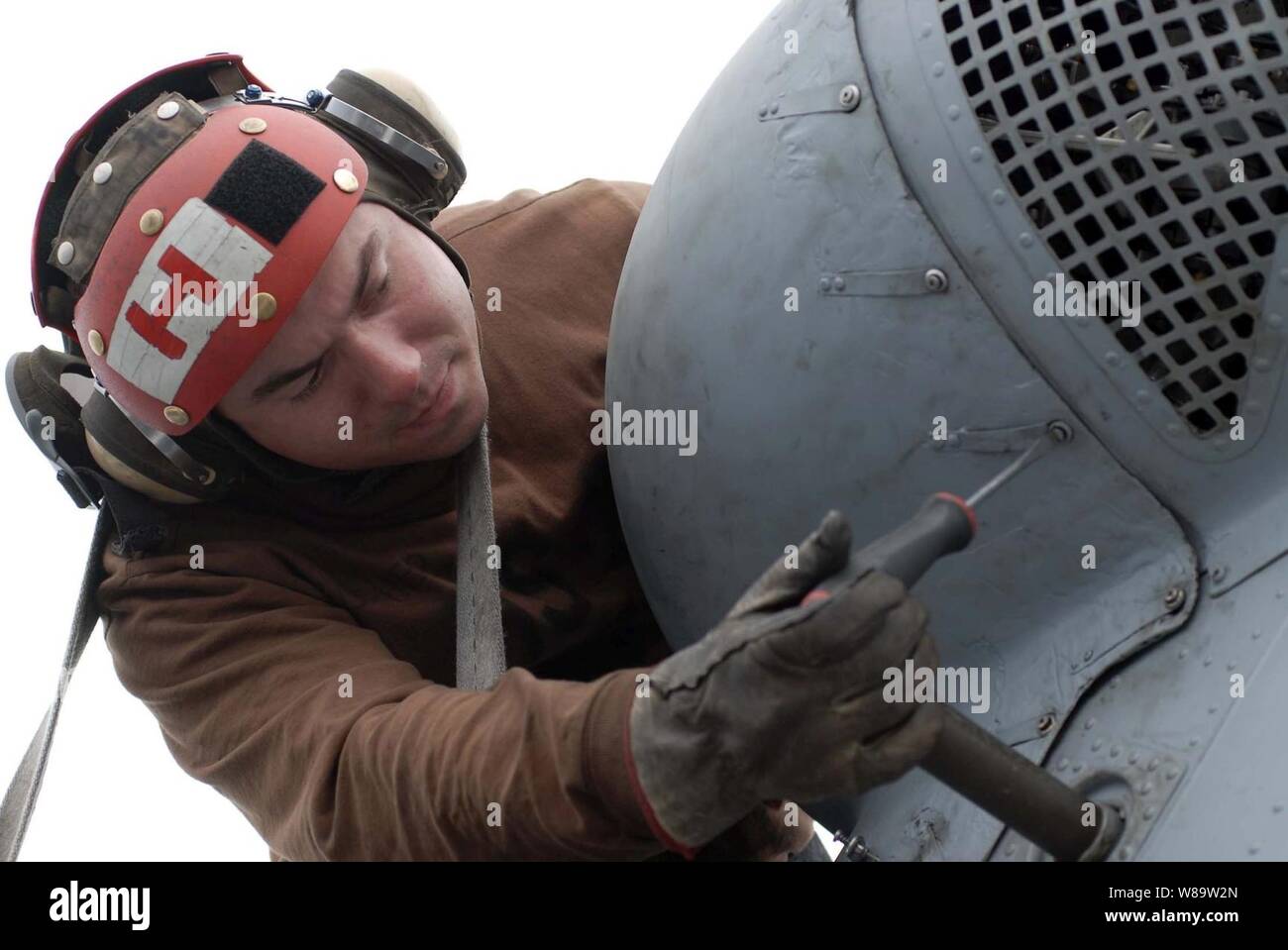 U.S. Navy Airman Aaron Gischer tightens the fasteners on a panel as he ...