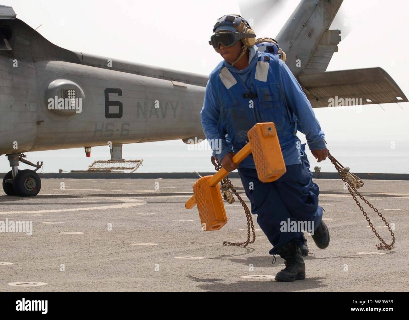 U.S. Navy Petty Officer 3rd Class Dontay Jones removes chocks from a ...