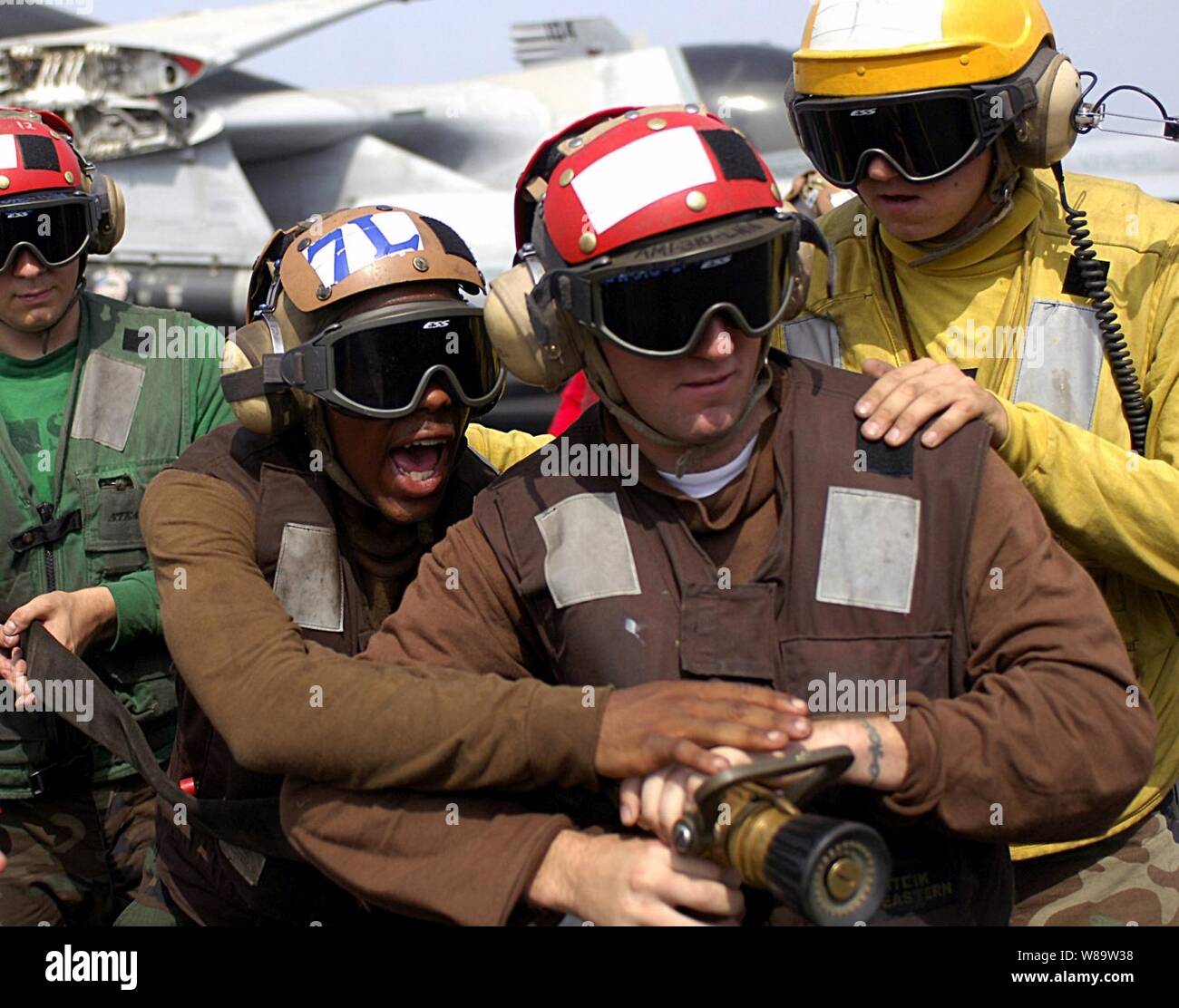 U.S. Navy crew members fight a simulated aircraft fire during a drill ...