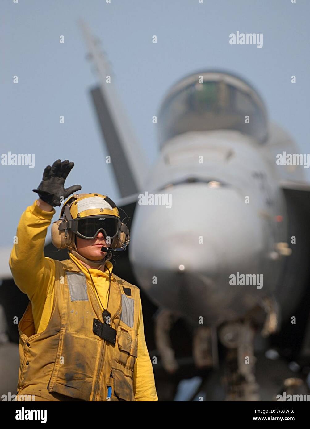 A U.S. Navy aircraft director signals to a tractor driver during flight ...