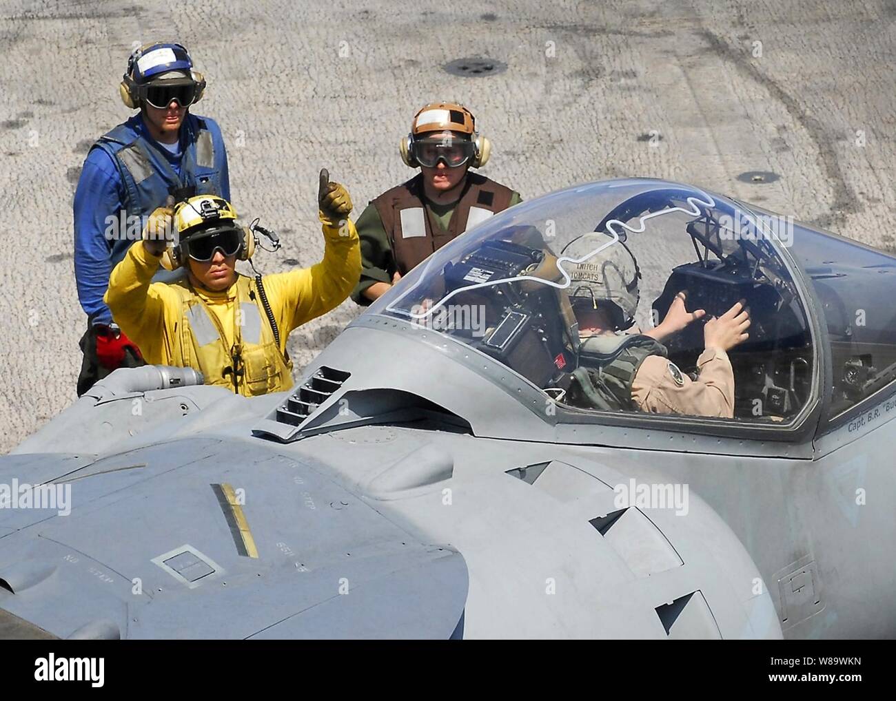 U.S. Navy flight deck crewmen use hand signals to communicate with the ...