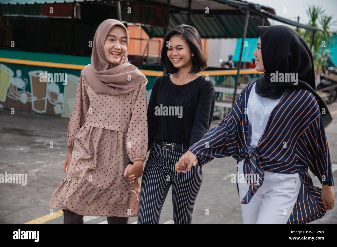 Three young people walking together Stock Photo - Alamy