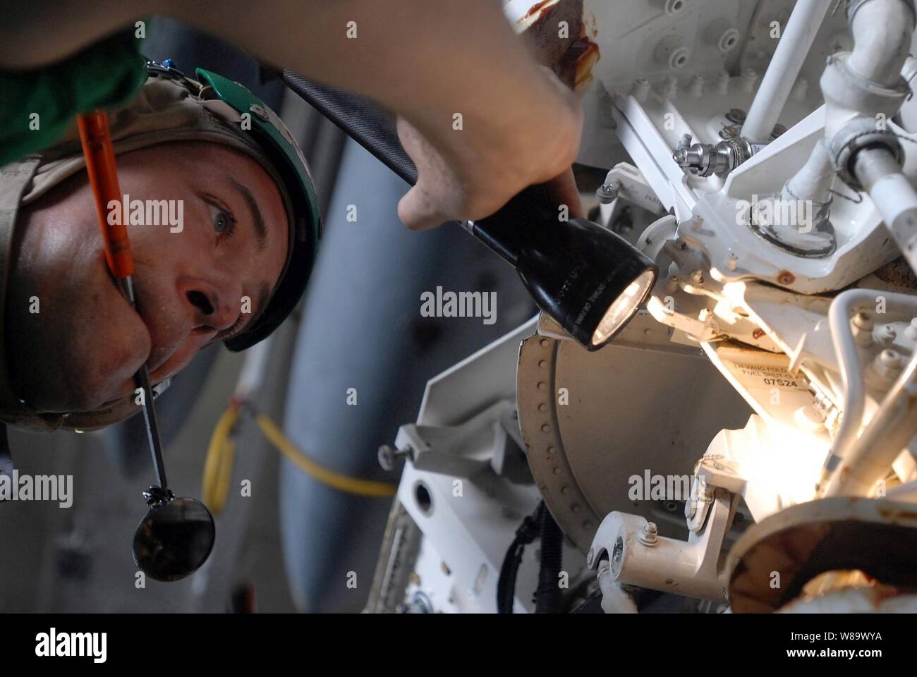U.S. Navy Petty Officer 2nd Class Kenneth Jacobsen shines a light into ...