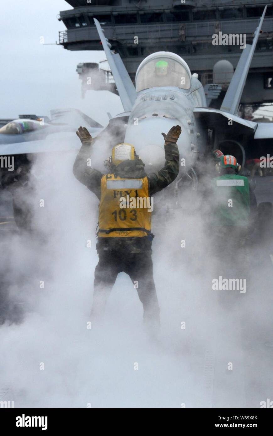 U.S. Navy Petty Officer 2nd Class Chad Yarbrough directs an F/A-18C ...