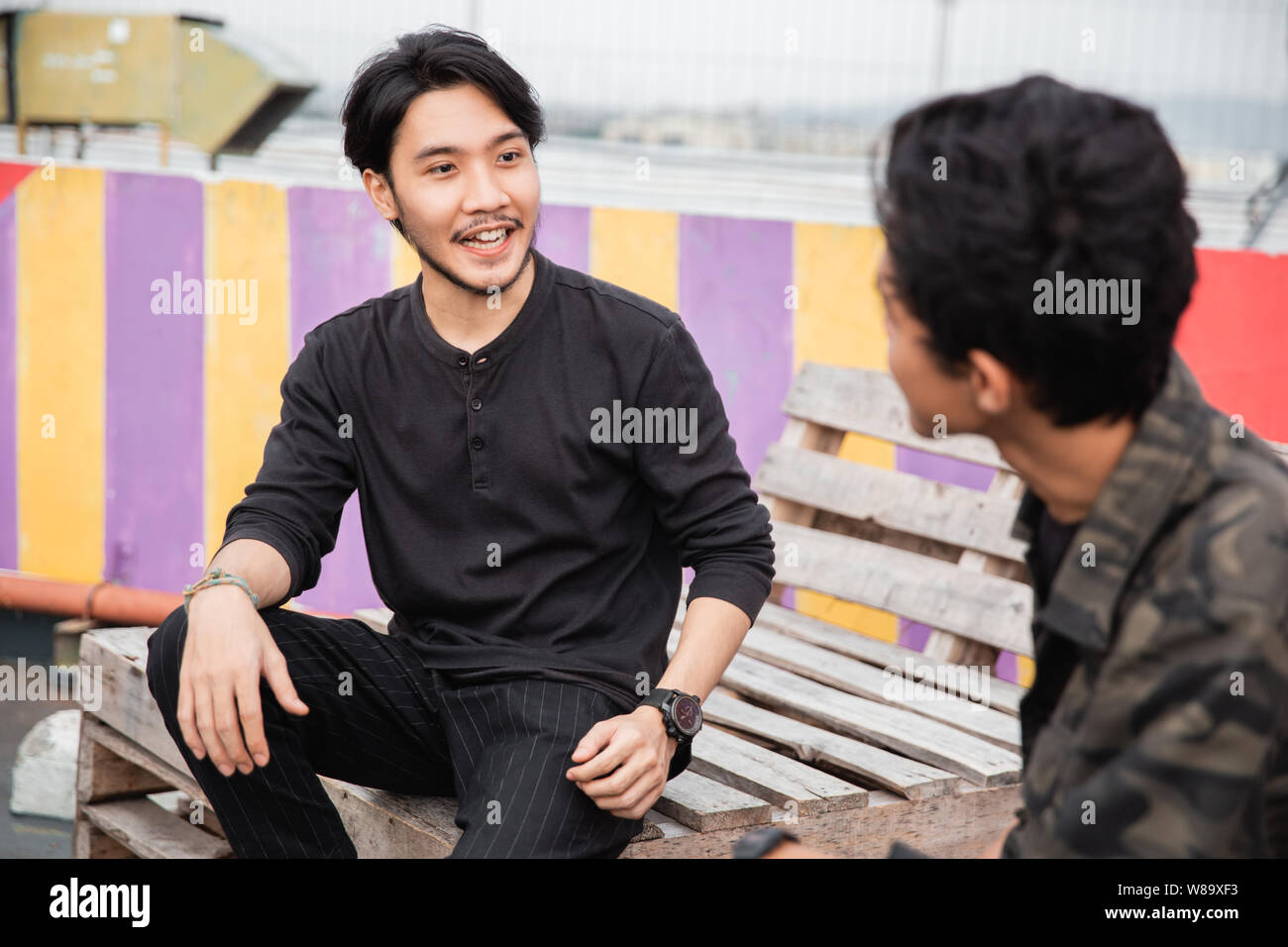 two friends chatting sitting on the wooden chair Stock Photo - Alamy