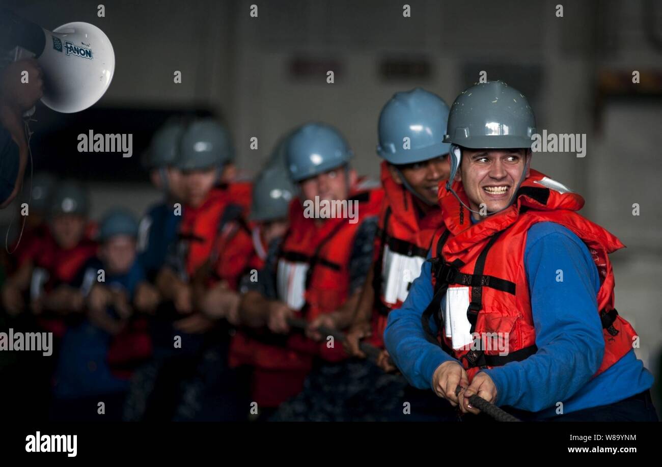 Sailors heave a line inside the hangar bay aboard the aircraft carrier ...