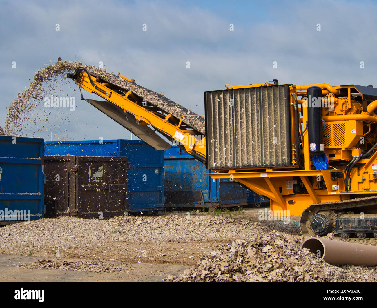 Industrial grinder discharge conveyer discharging recycled cardboard ...