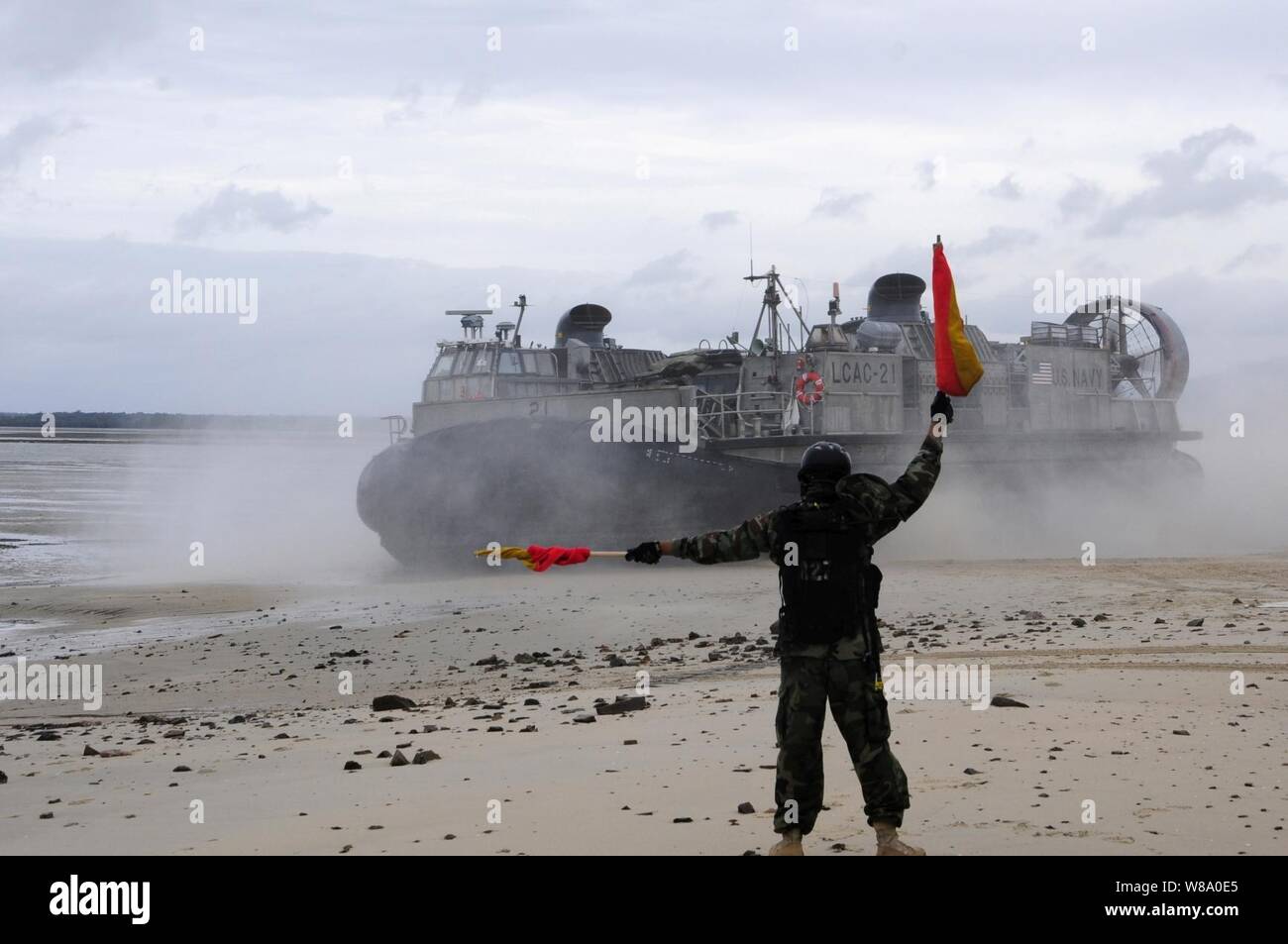 A U.S. Navy sailor with Beachmaster Unit 1 directs a landing craft, air ...