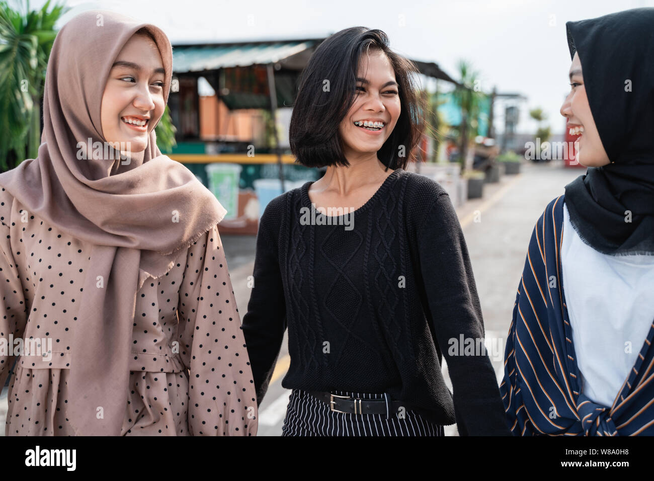 Three young people walking together Stock Photo - Alamy