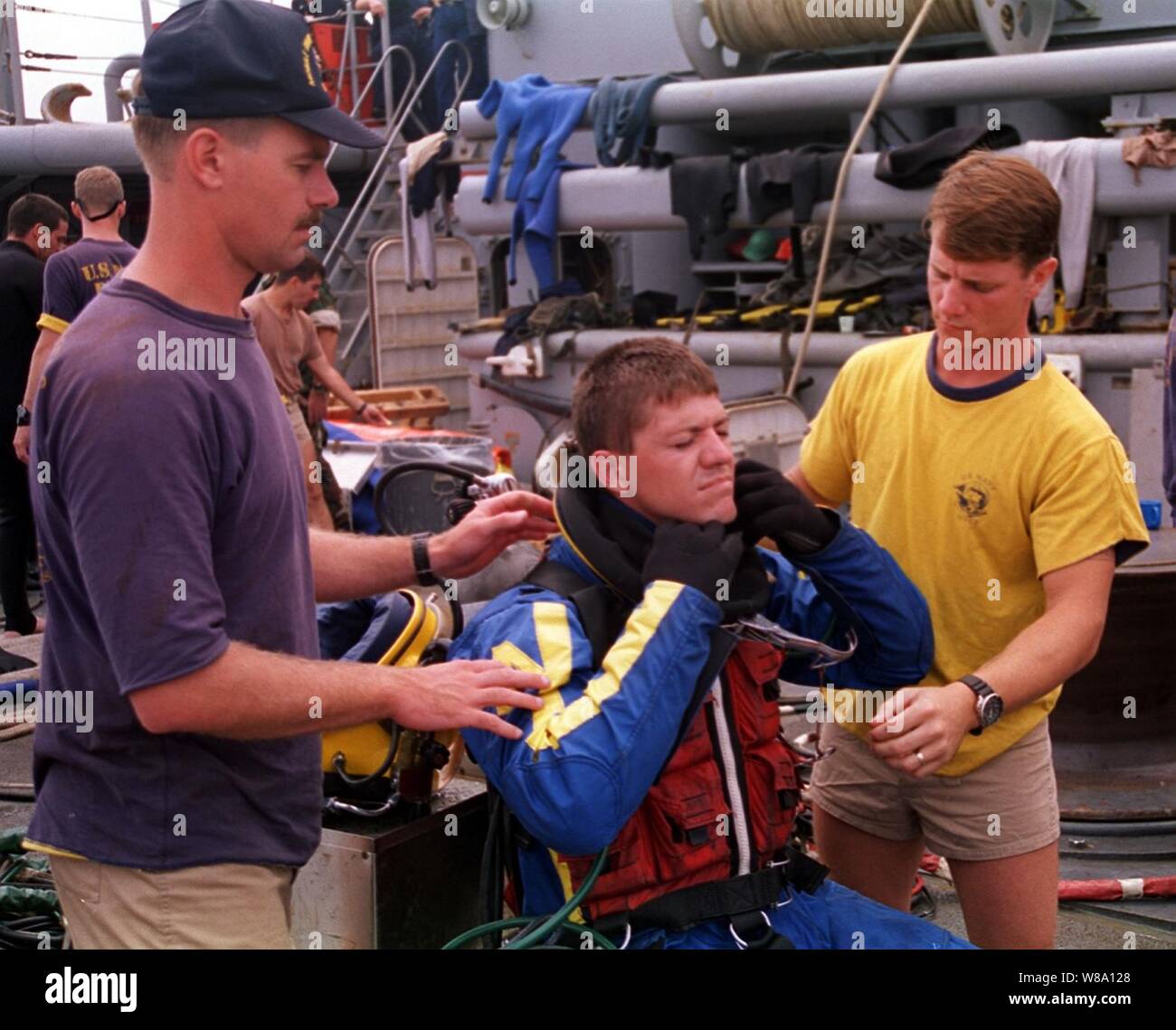 U.S. Navy Diver Petty Officer 2nd Class Brad Fleming (center) is being ...