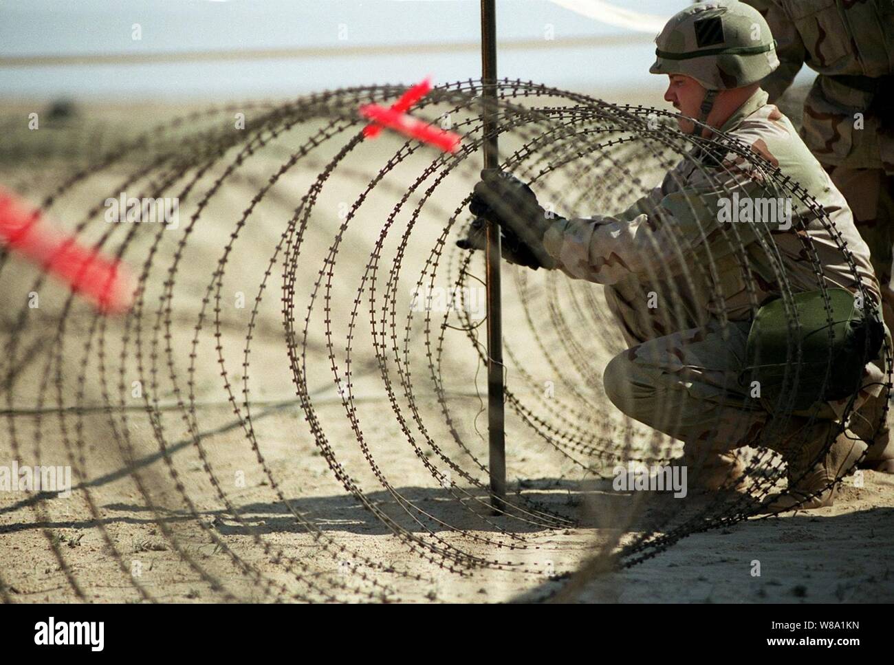 U.S. Army Sgt. Troy Brayton works on coils of concertina wire on March ...
