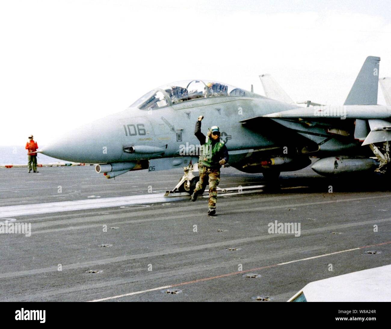 A flight deck crew member gives a thumbs up signal indicating the F-14 ...