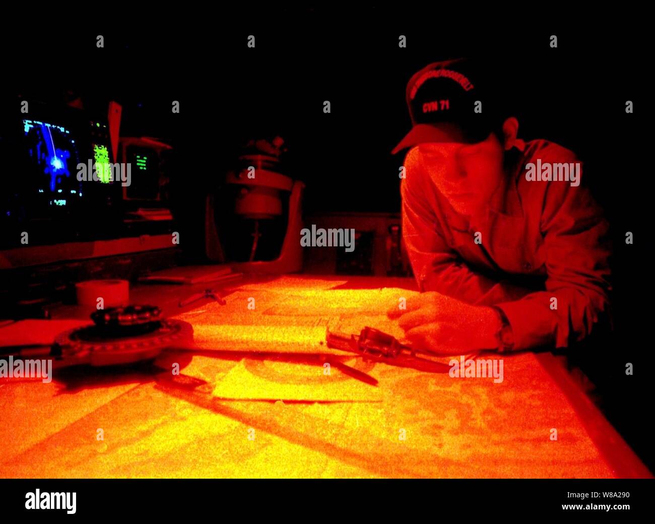 Seaman Apprentice Timothy Lee, U.S. Navy, works in the glow of red ...