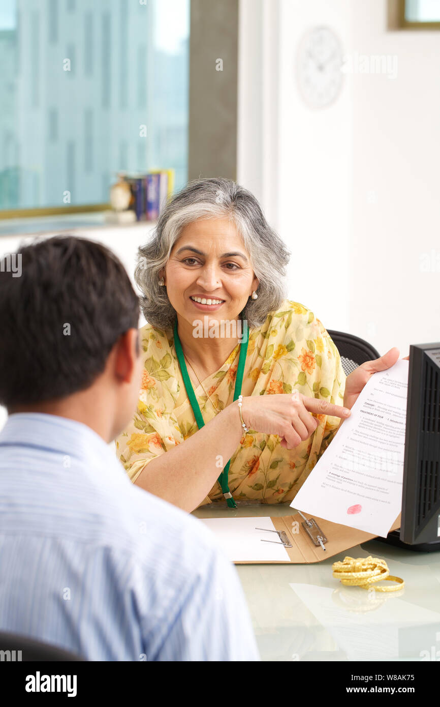 Bank manager showing the papers of gold loan to her customer Stock ...