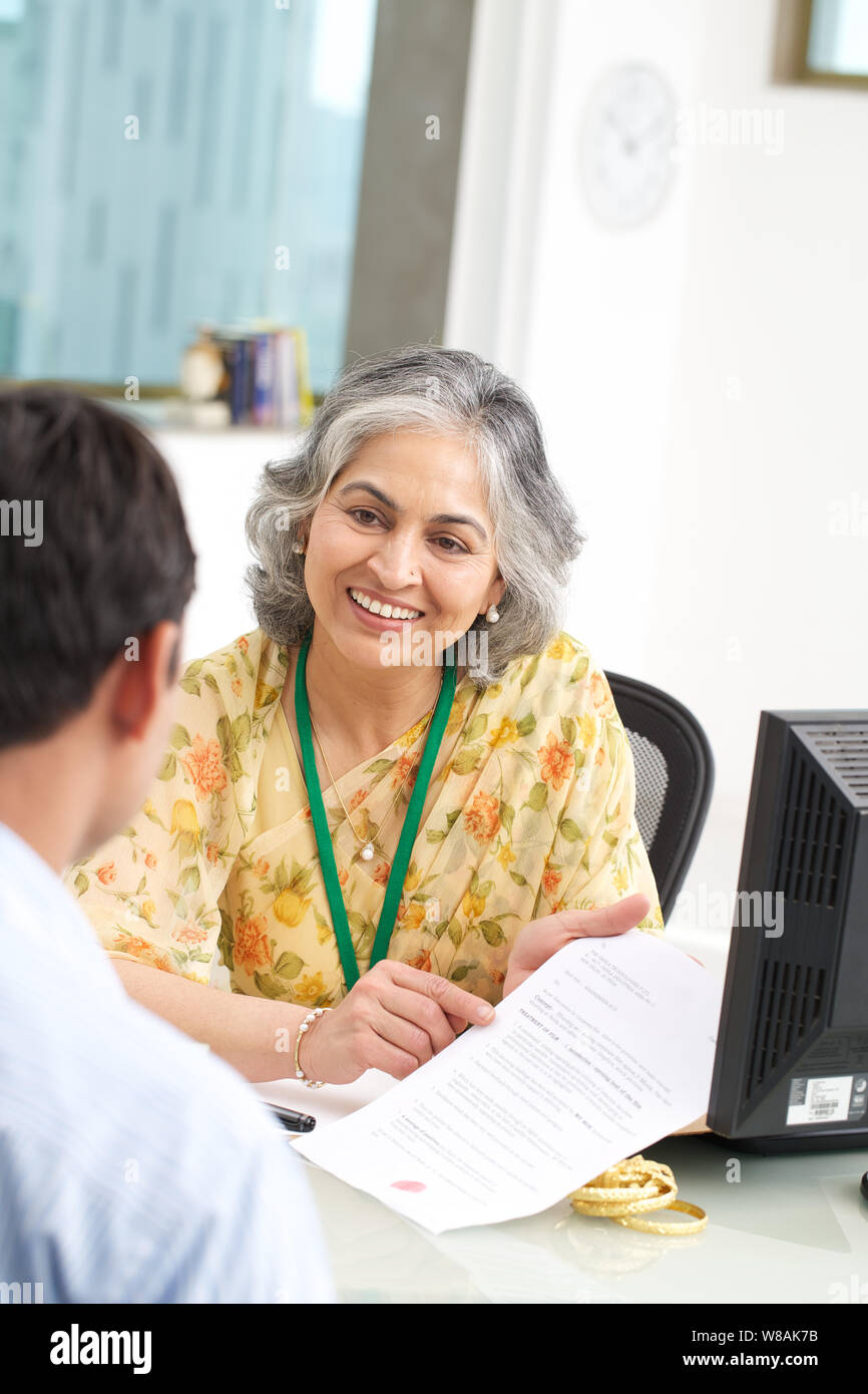 Bank manager showing the papers of gold loan to her customer Stock ...