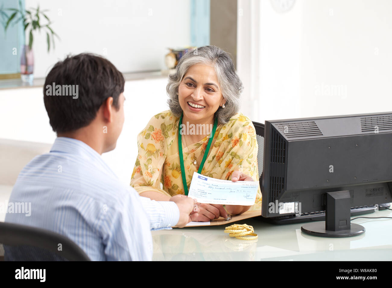 Customer receiving cheque to bank manager as gold loan Stock Photo - Alamy