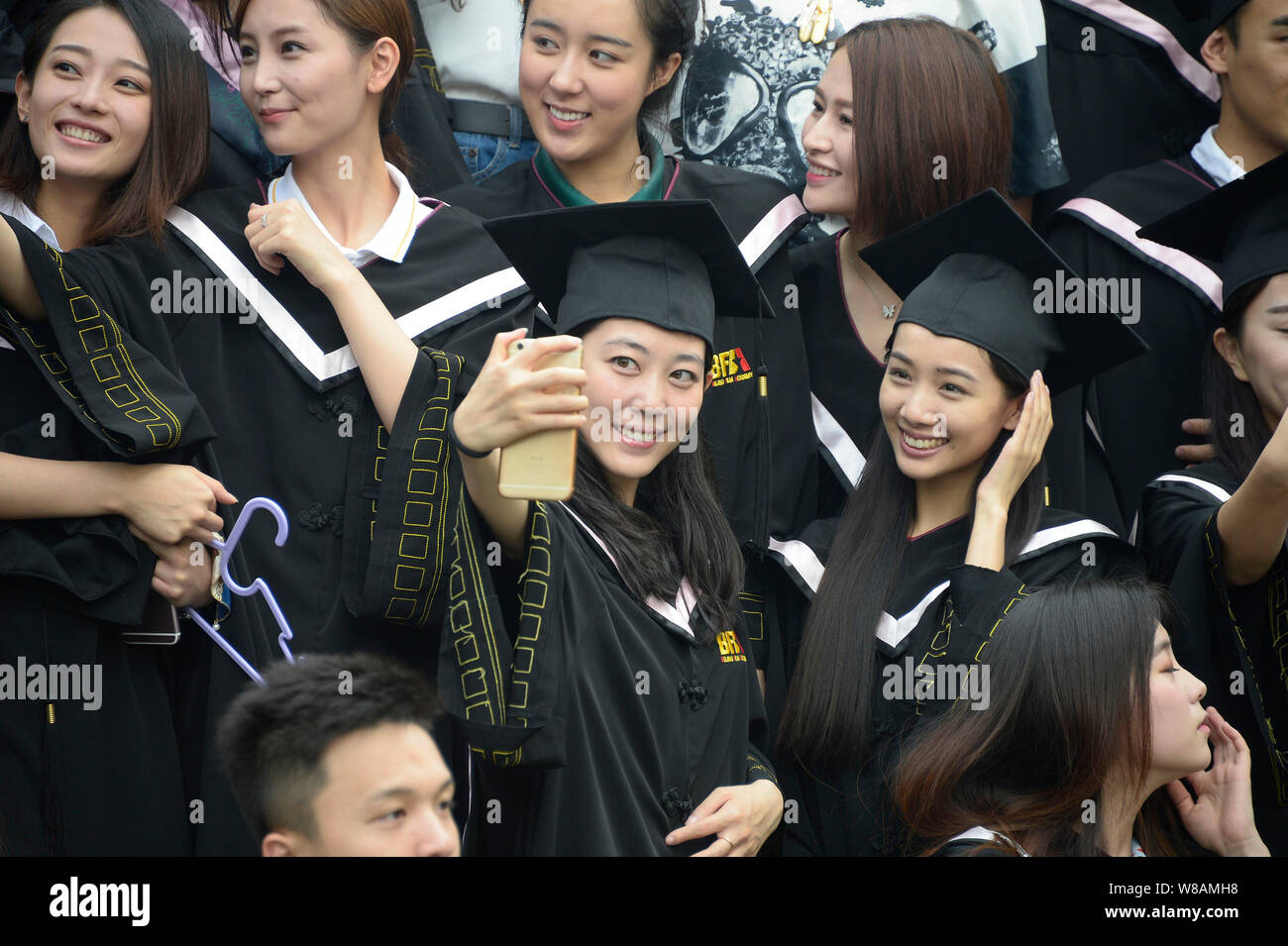 Chinese graduates dressed in academic gowns take selfies during a ...