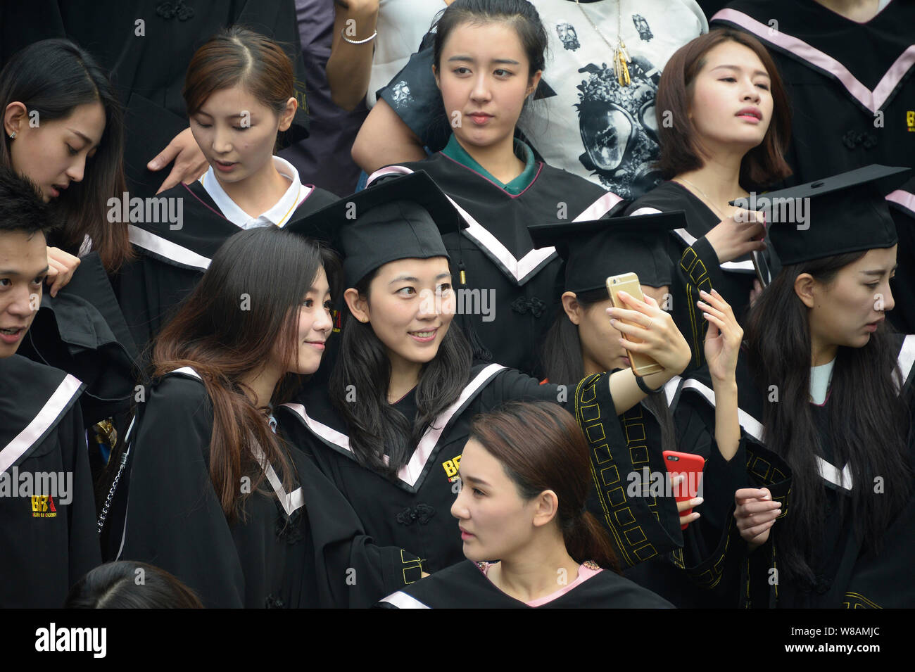 Chinese graduates dressed in academic gowns take selfies during a ...
