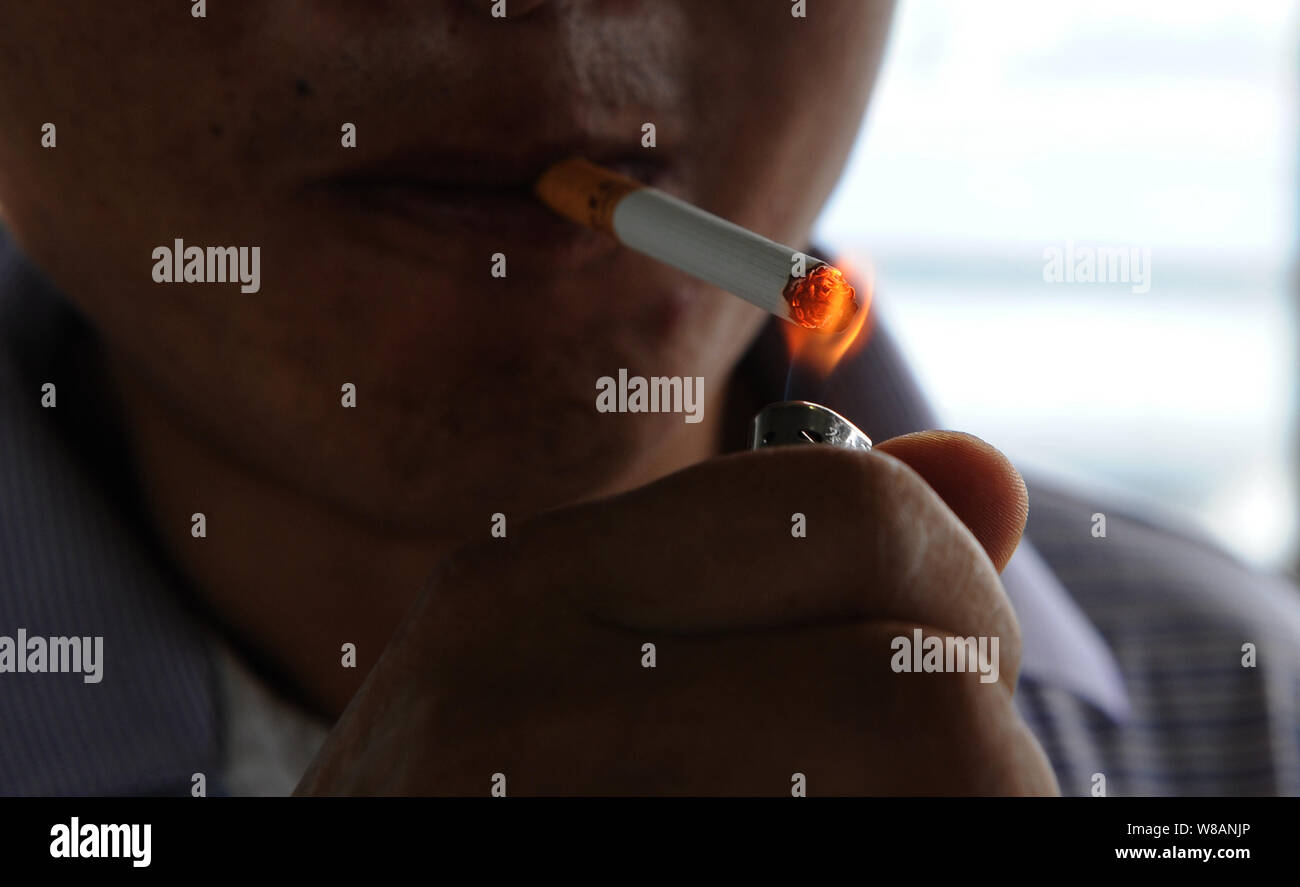 --FILE--A Chinese smoker lights up a cigarette in a smoking room at the ...
