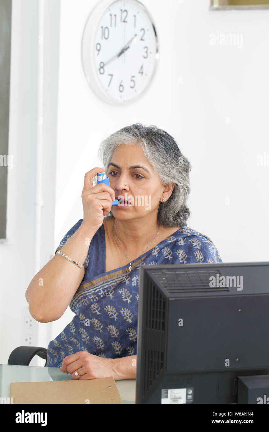Businesswoman using asthma inhaler Stock Photo - Alamy