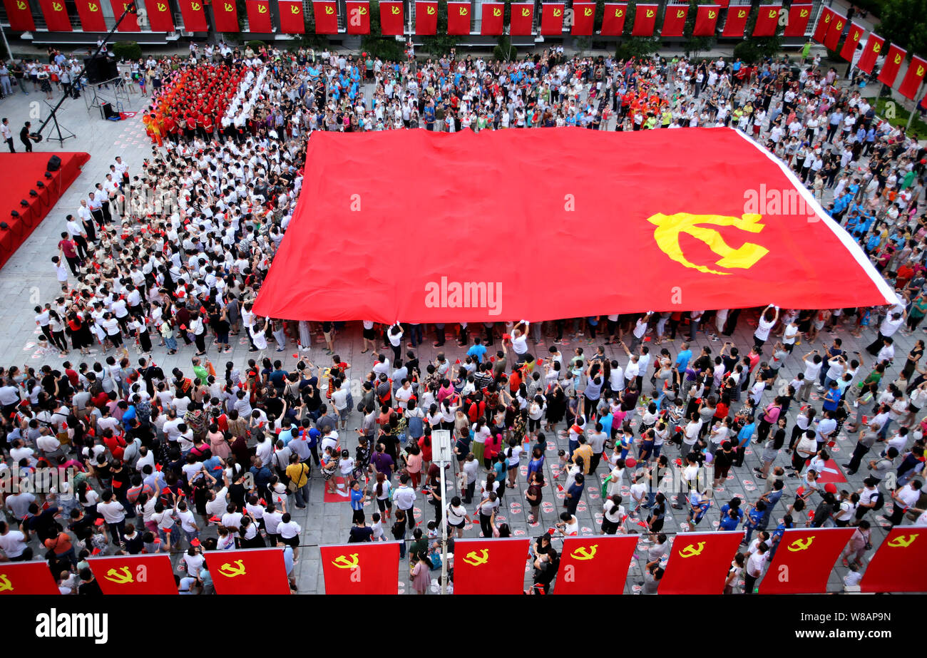Local Chinese residents pass on a giant flag of the Communist Party of ...