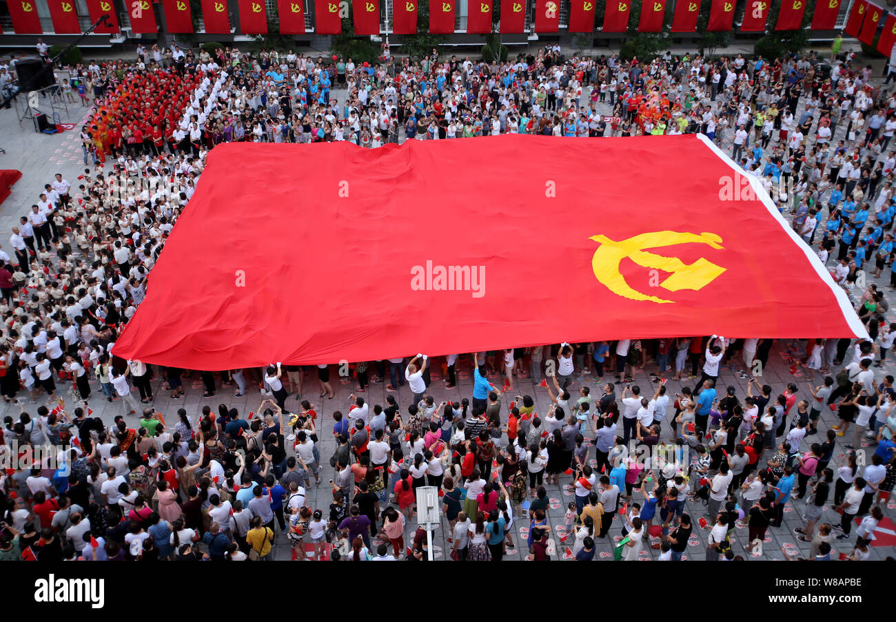 Local Chinese residents pass on a giant flag of the Communist Party of ...