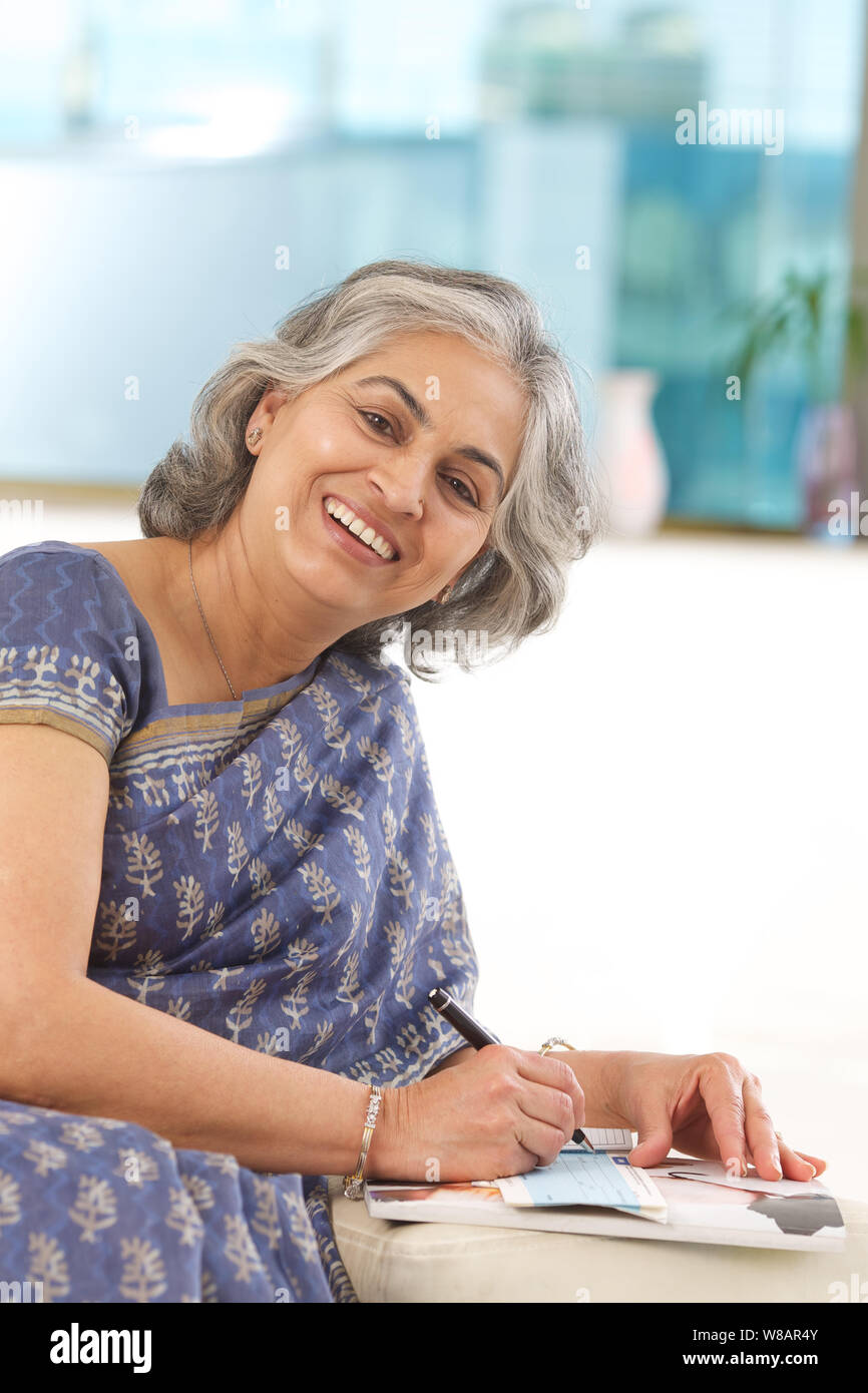 Senior woman signing a cheque Stock Photo - Alamy