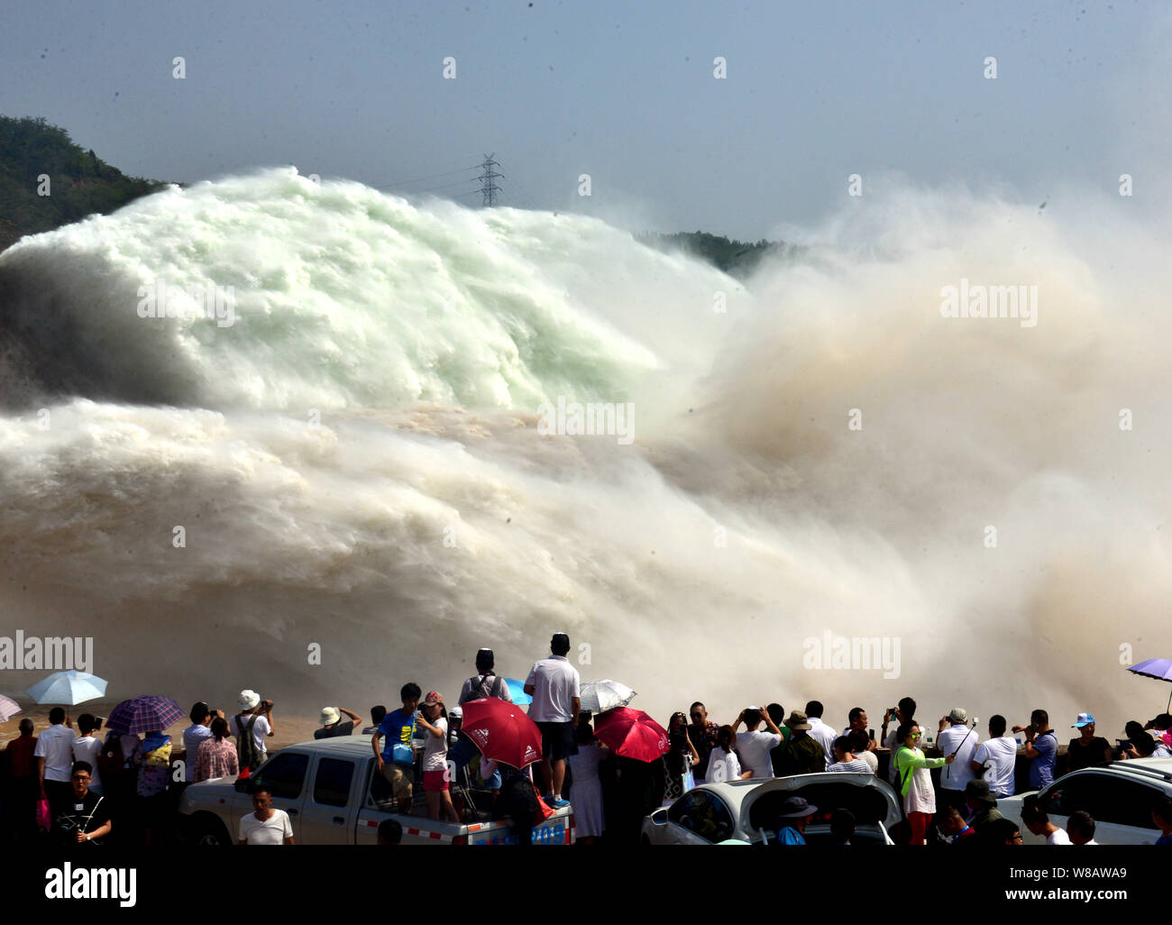 People watch water gushing out from the Xiaolangdi Dam during a silt ...