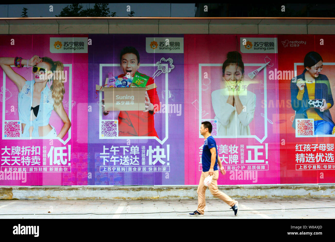 A pedestrian walk past an advertisement of online shopping site Suning ...