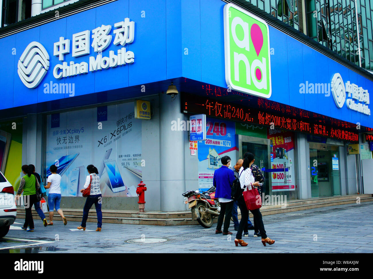 Pedestrians walk past a branch of China Mobile in Yichang city, central ...