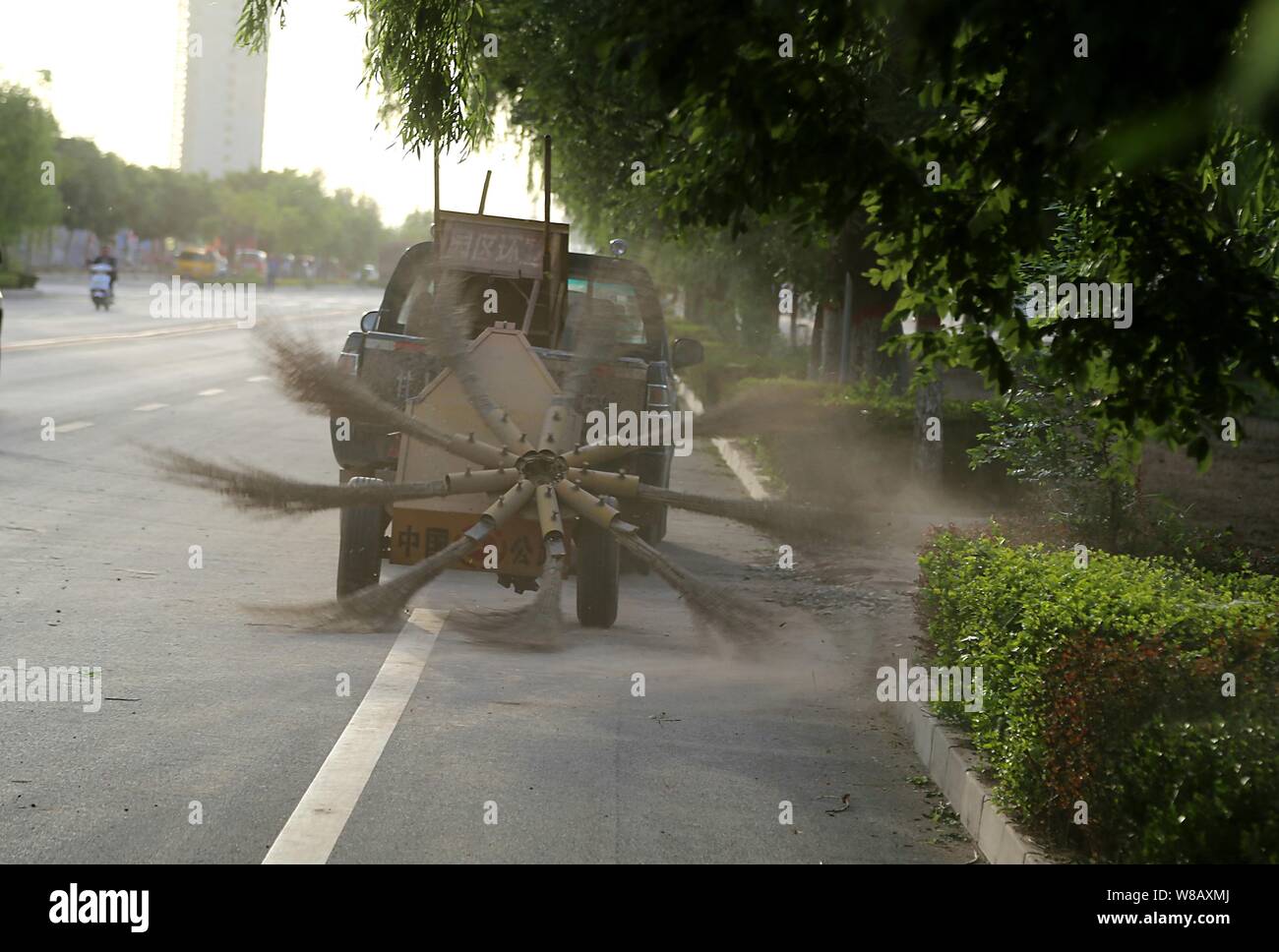 A van pulling a cleaning machine equipped with nine brooms travels on a ...