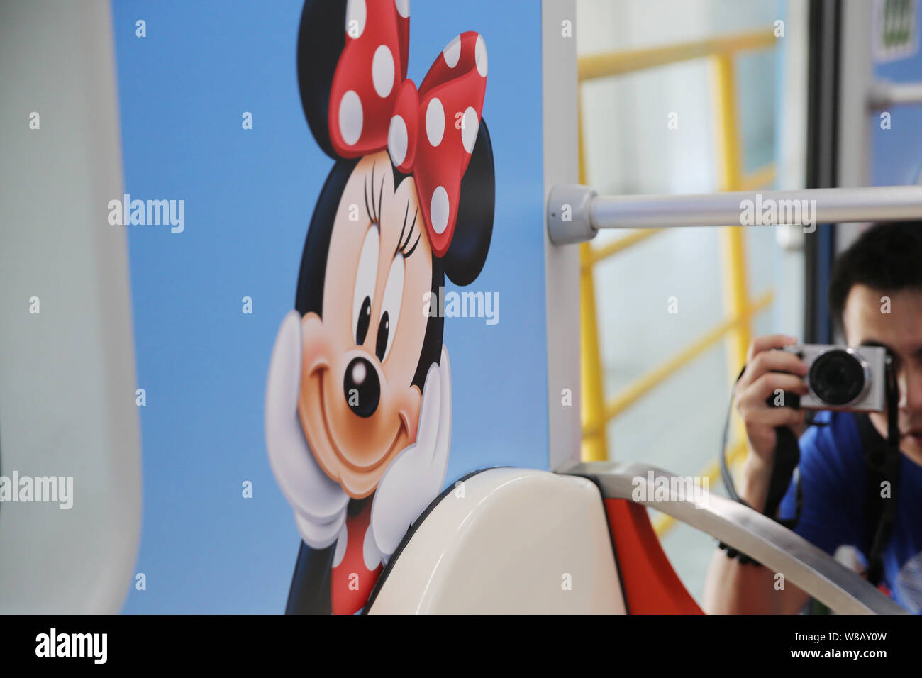 A man takes a picture of an image of Minnie Mouse in a Disney-themed ...