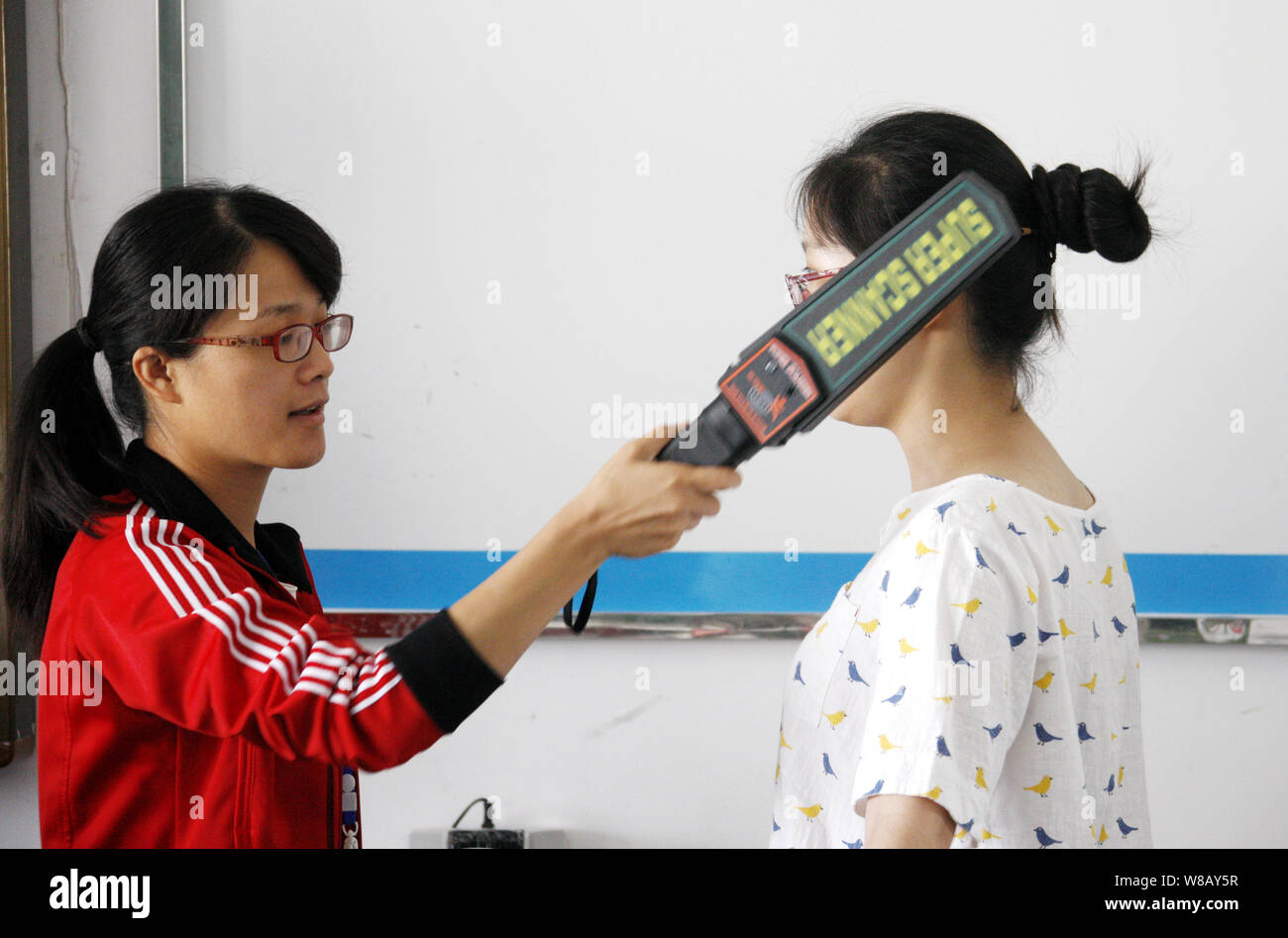 A Chinese invigilator scans a student for security check in the ...