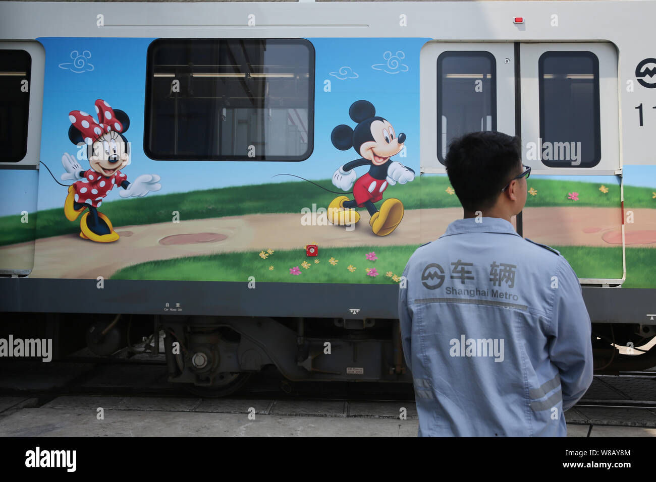 A Chinese worker looks at a Disney-themed subway train of the Shanghai ...