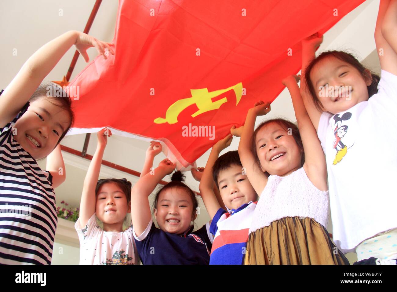 Young Chinese kids hold up a flag of the Communist Party of China (CPC ...