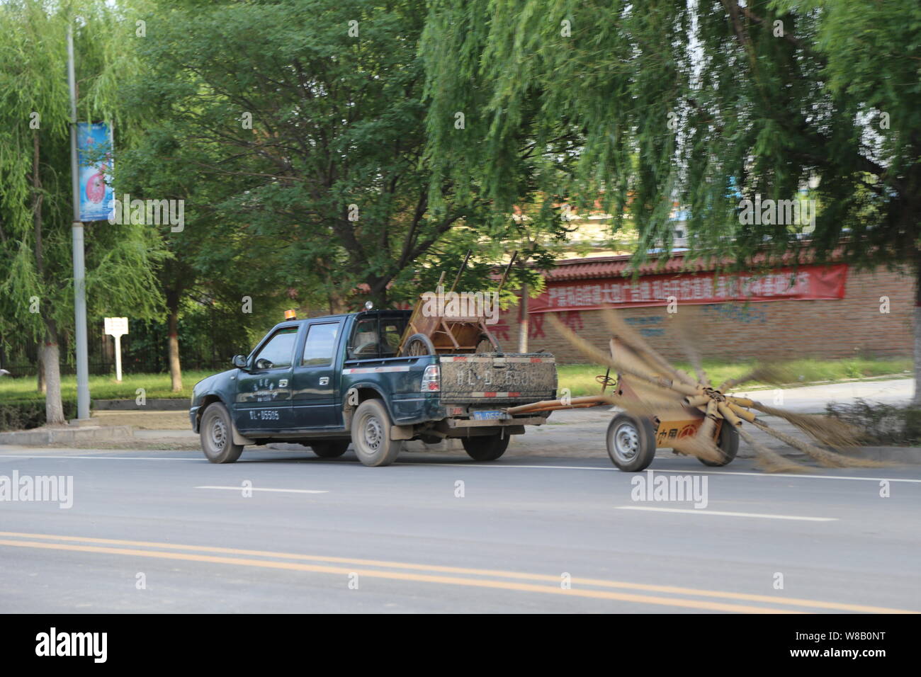 A van pulling a cleaning machine equipped with nine brooms travels on a ...