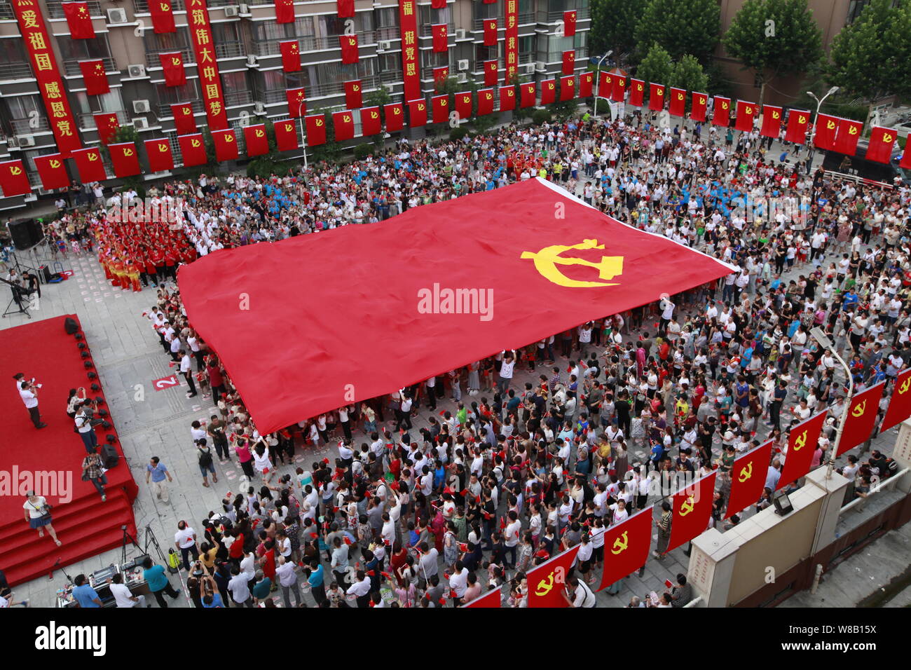 Local Chinese residents pass on a giant flag of the Communist Party of ...