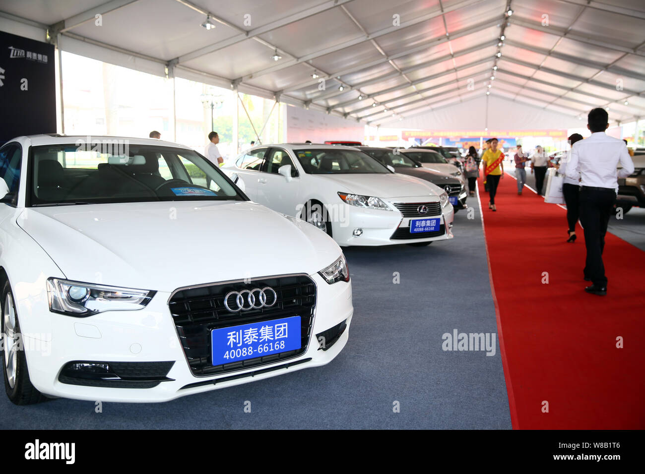 --FILE--Visitors look at parallel-imported cars on display during a ...