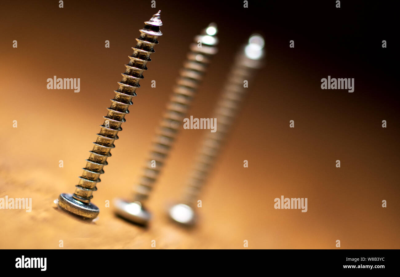 Close up of three long neck standing screws on wooden background ...